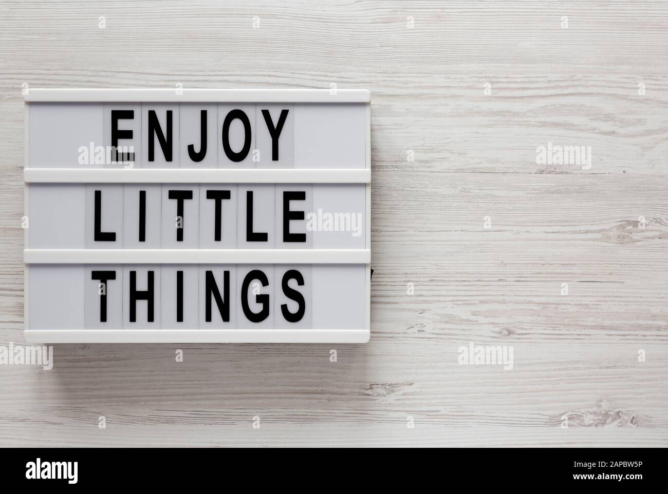 'Enjoy little things' words on a lightbox on a white wooden surface ...