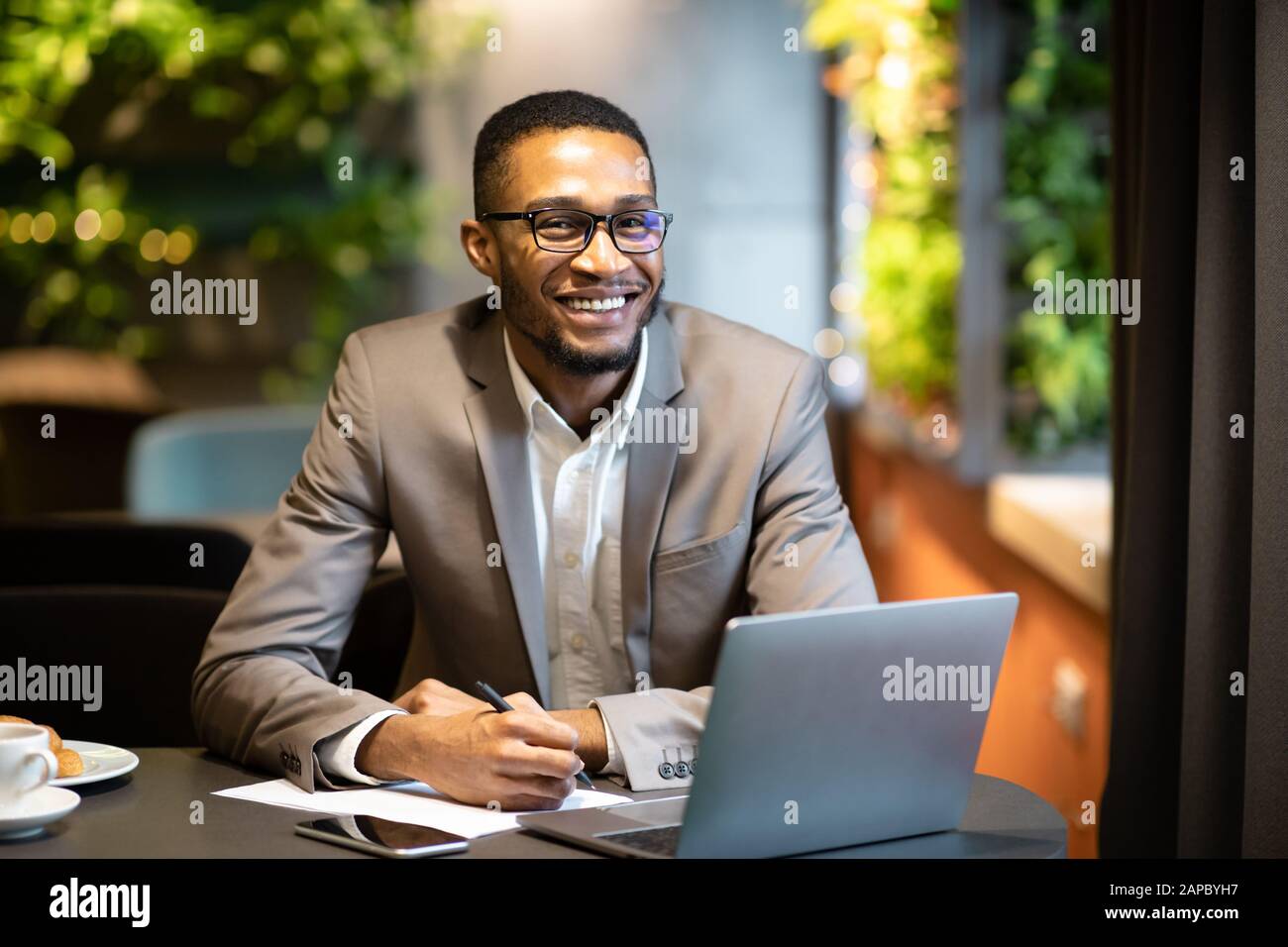Black business guy taking notes in notebook Stock Photo - Alamy