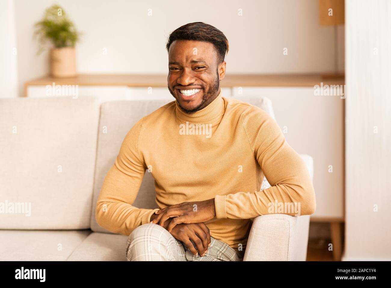Happy African American Man Smiling Sitting On Sofa At Home Stock Photo ...