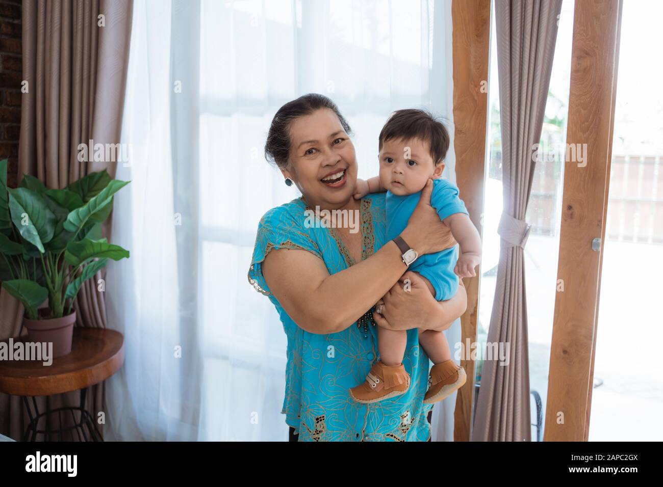 Grandma stand with carrying little grandson Stock Photo - Alamy
