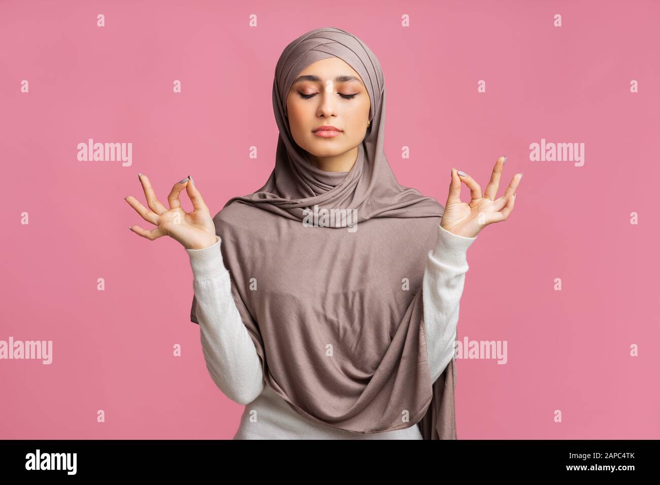 Relaxed muslim girl in hijab meditating over pink background Stock ...