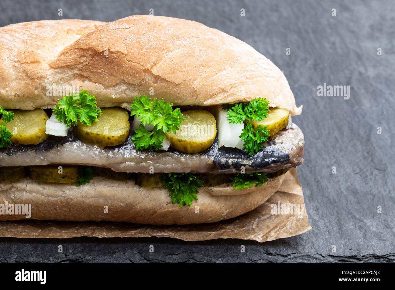 Traditional Dutch sandwich with herring and pickles on black stone ...