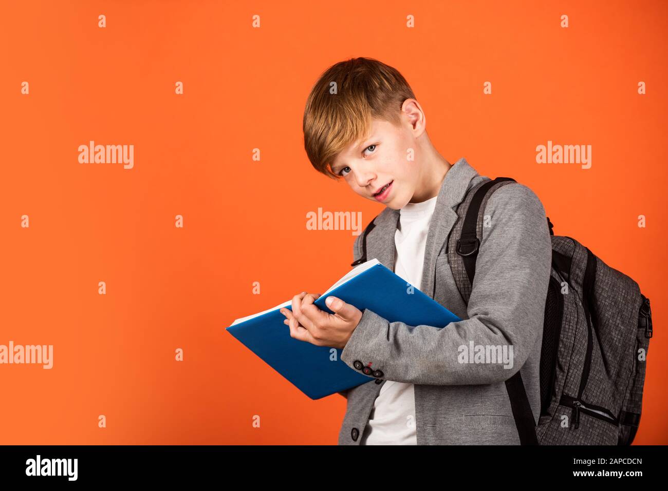 Final exam. Little child take exam brown background. Small boy write in ...
