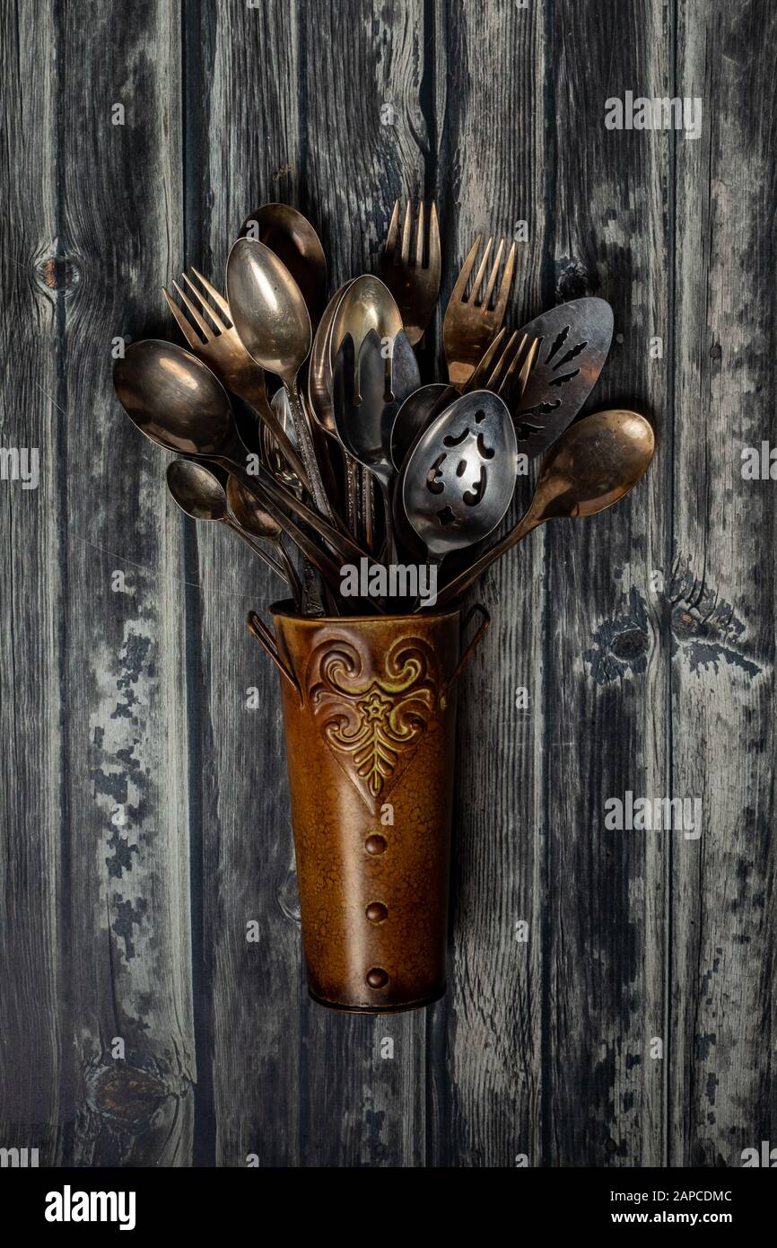 A top down view of a bronze metal vase filled with antique cutlery and ...