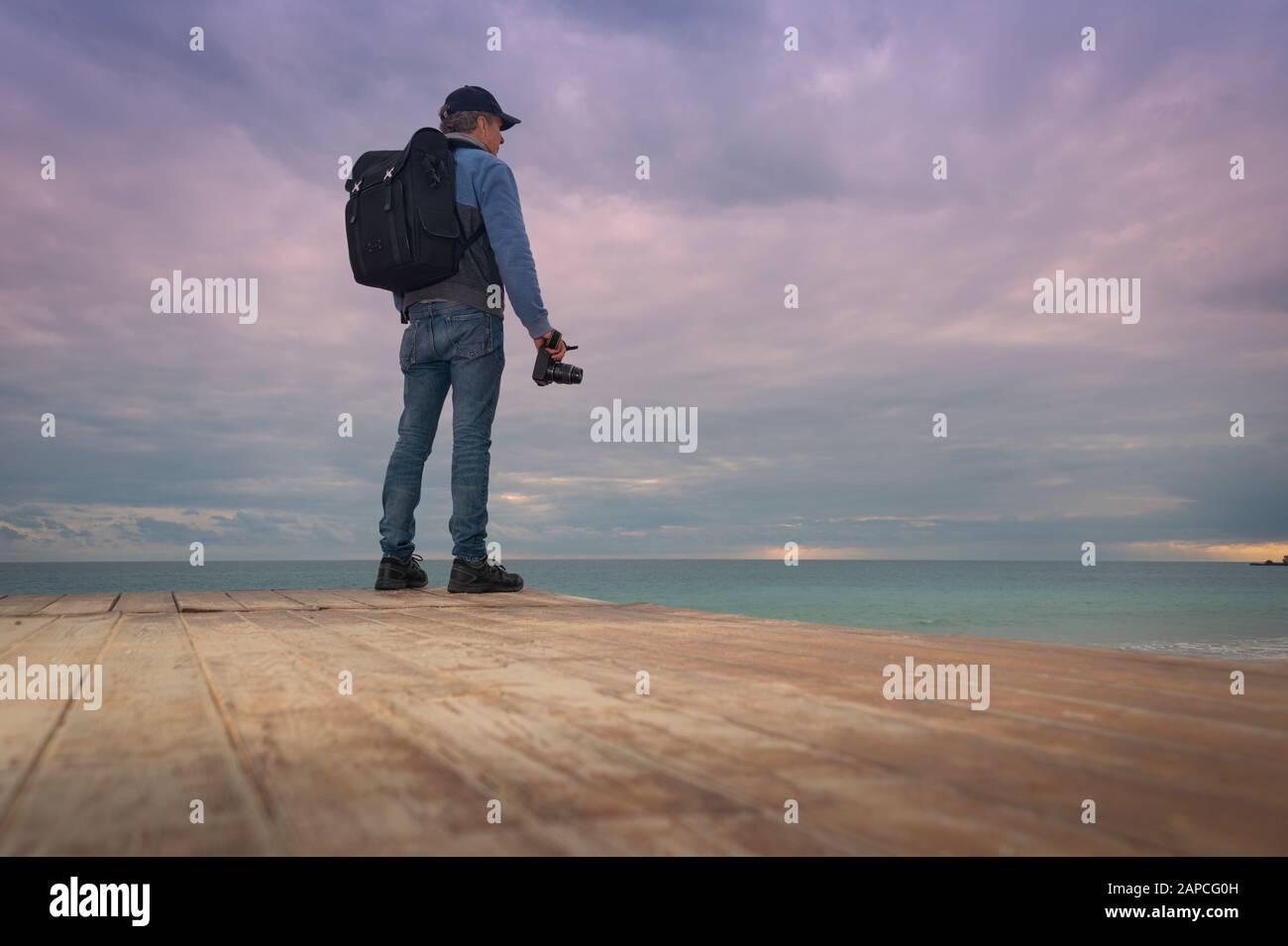 Back view of a photographer carrying a camera looking out over the ...