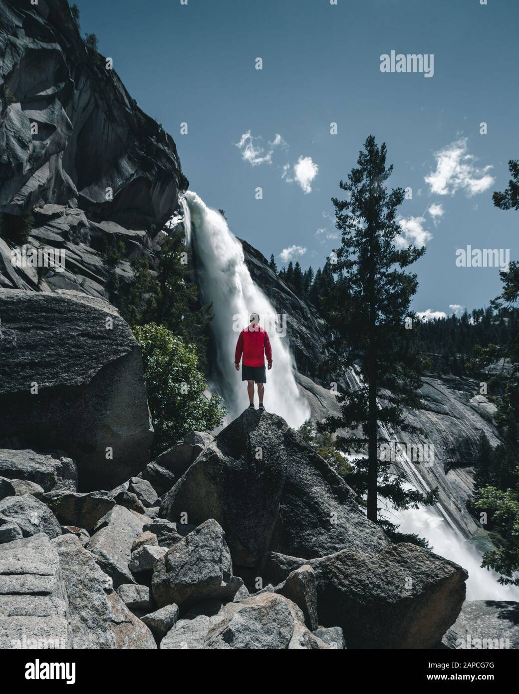 An adventurous guy standing in front of a huge waterfall in the ...