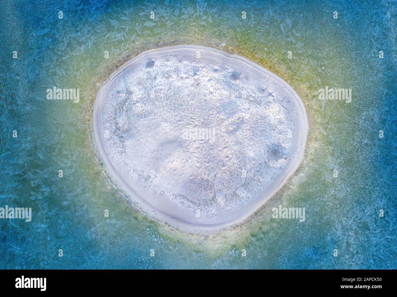 A small empty island in the middle of a frozen lake, winter landscape ...
