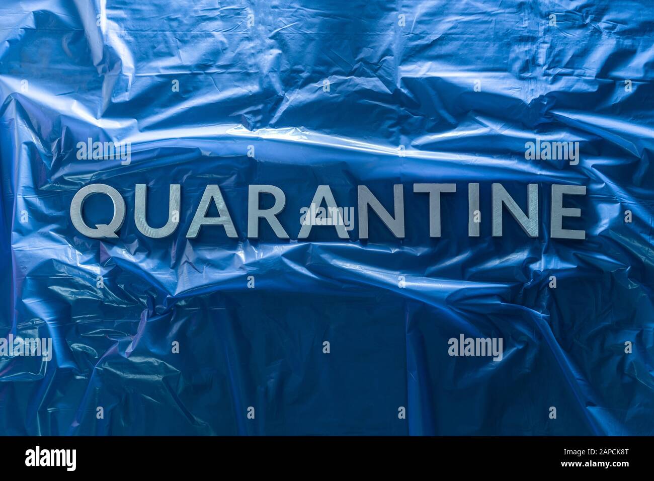 the word quarantine laid with silver letters on crumpled blue plastic ...
