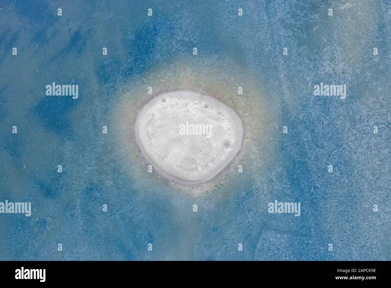 A small empty island in the middle of a frozen lake, winter landscape ...