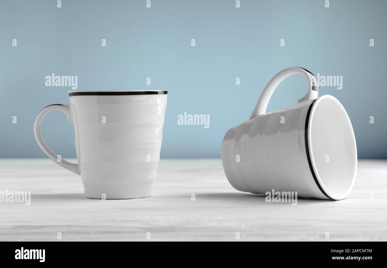 Two blank white mugs on white table and blue background. White blank ...