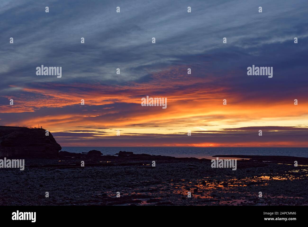 Dawn at the Rocky North beach of Arbroath with the red and orange light ...