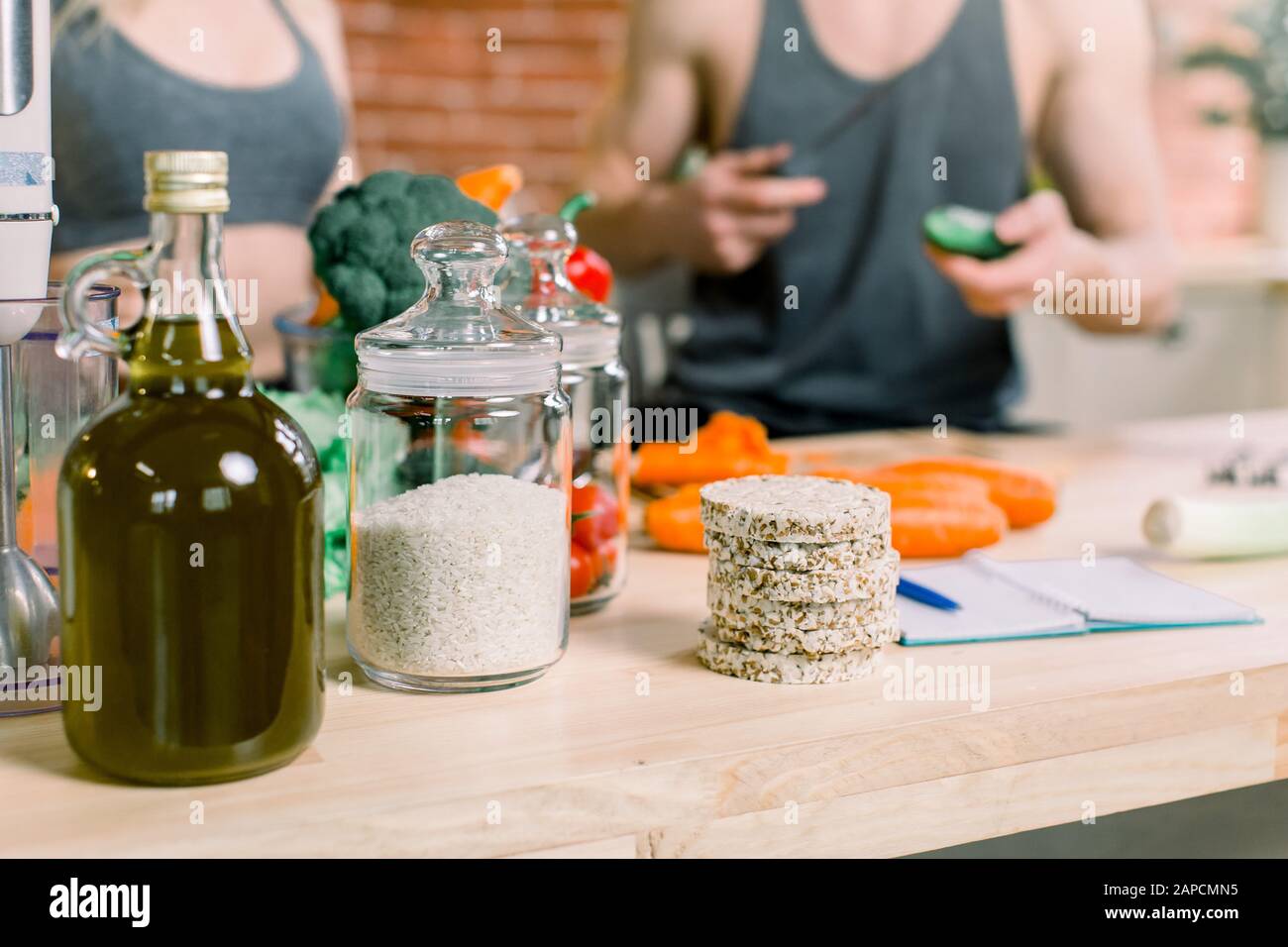 Beautiful young sports people are talking and smiling while cooking ...