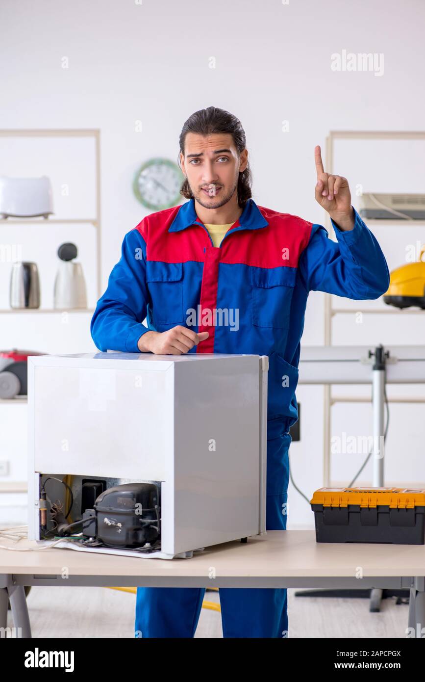 The young male contractor repairing refrigerator at workshop Stock ...