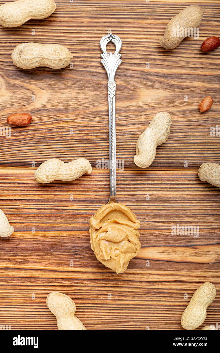 Vintage spoon with creamy peanut butter on a brown wooden table. Near ...