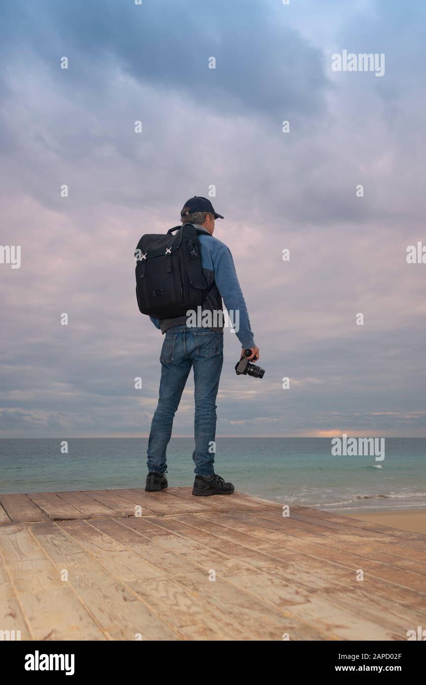 Back view of a photographer carrying a camera looking out over the ...
