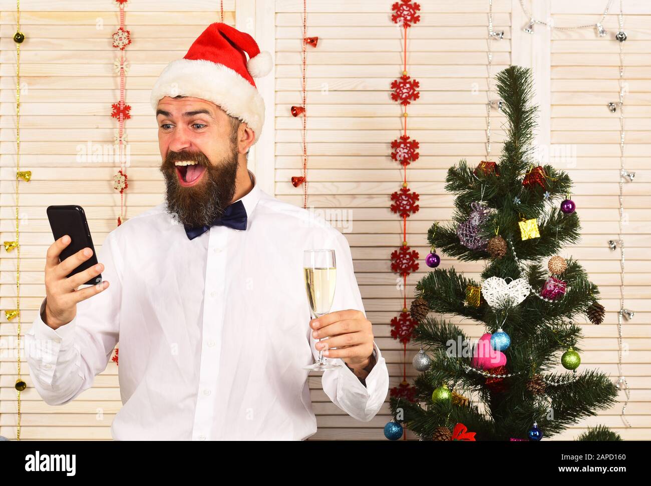 Guy near Christmas tree on wooden wall background. Santa Claus in red ...