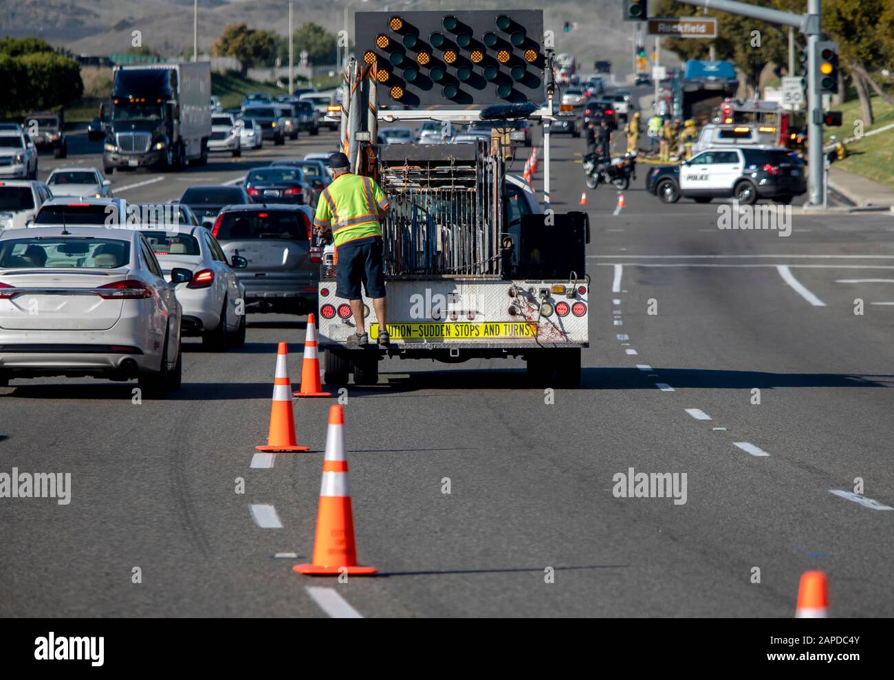 Worker behind utility truck placing bright orange traffic cones on ...