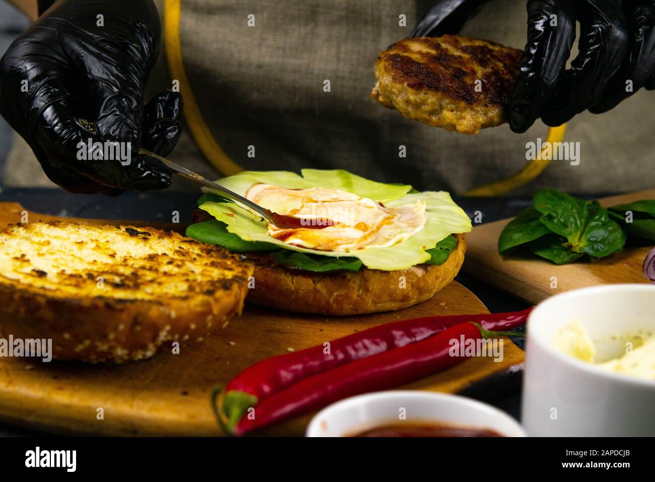 Process of cooking burgers. Cropeed view of chef hands in black gloves ...