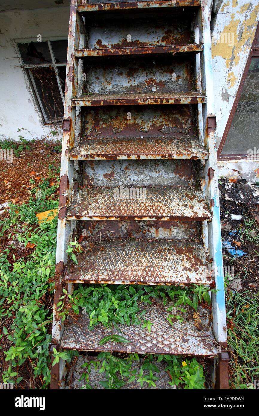 Old abandoned rusty steel stairs overgrown with grass at summer day ...