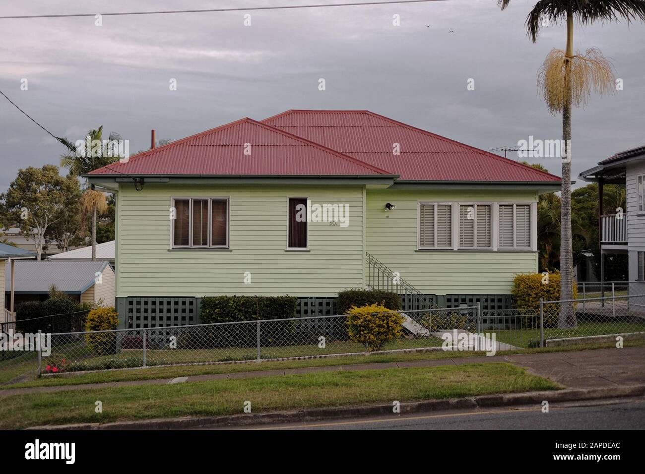 Post-war low set weatherboard suburban house painted green with ...