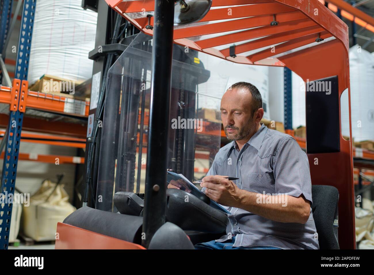 forklift driver studying paperwork on clipboard Stock Photo - Alamy