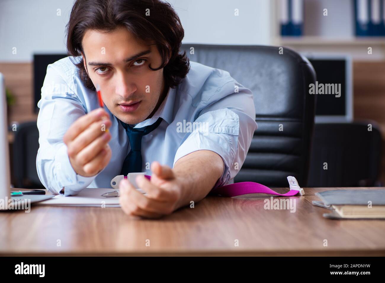 The young man having problems with narcotics at workplace Stock Photo ...