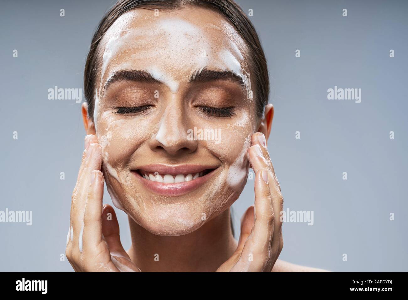 Amazing girl washing her face with foam against light background Stock ...
