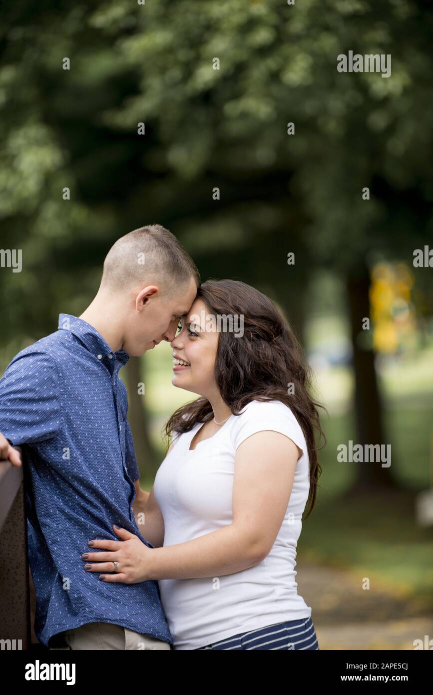 Couple touching foreheads in a park under sunlight with a blurry ...