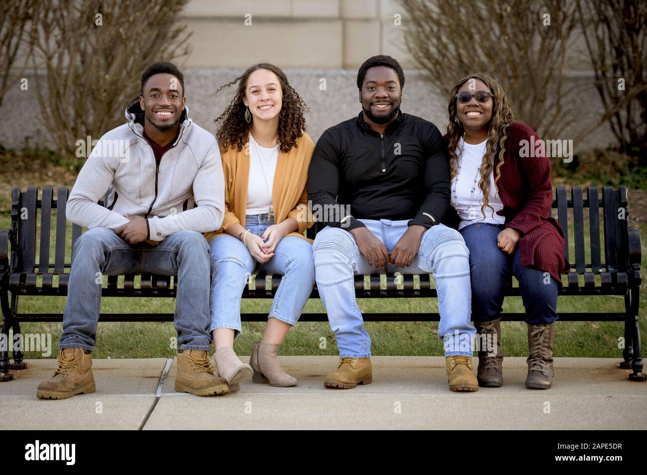 Group of people sitting on a bench in a park under sunlight with a ...