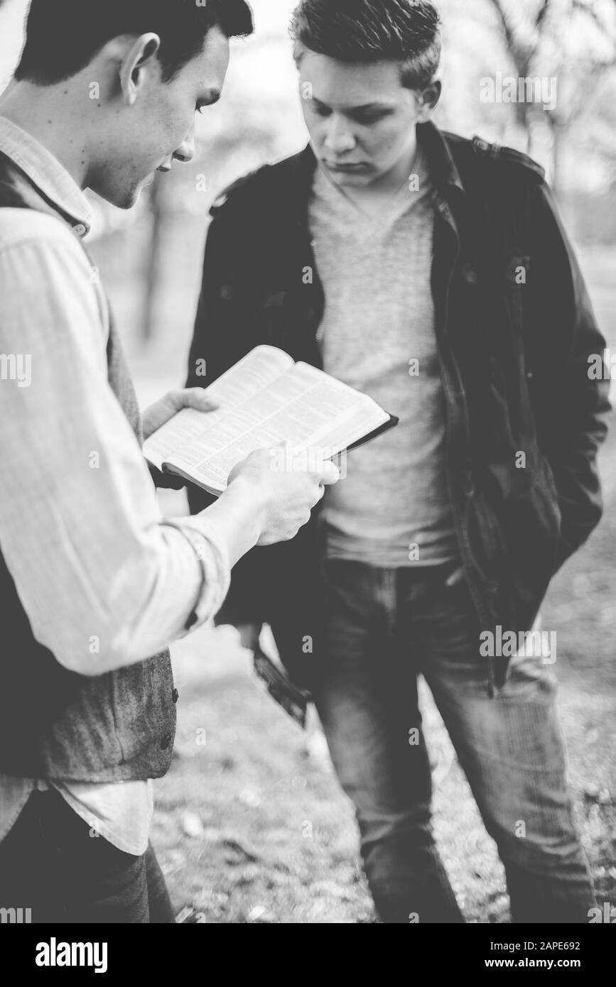 Greyscale of men discussing the bible in a park under sunlight with a ...