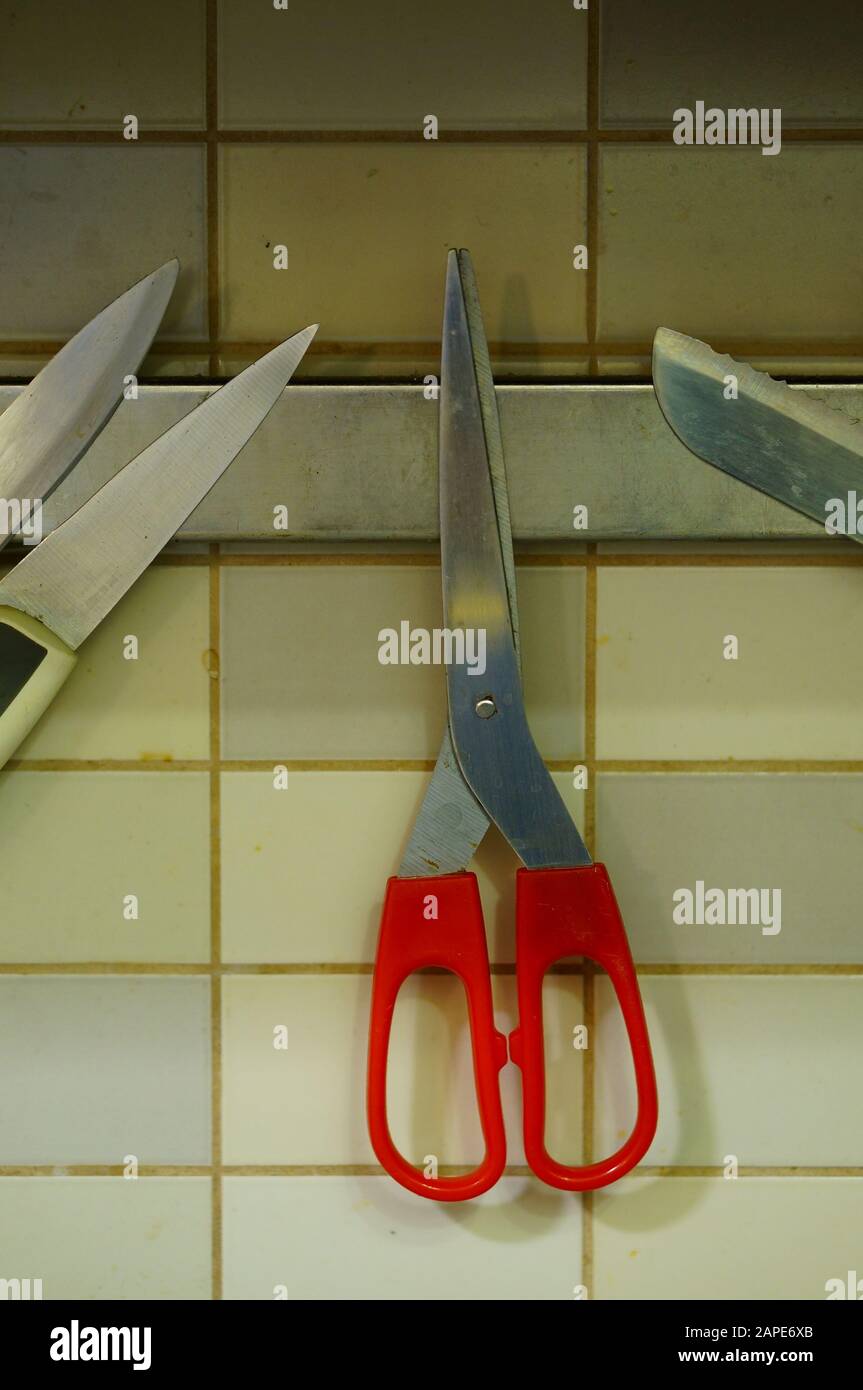 Vertical shot of red scissors attached to a magnet on a wall Stock ...