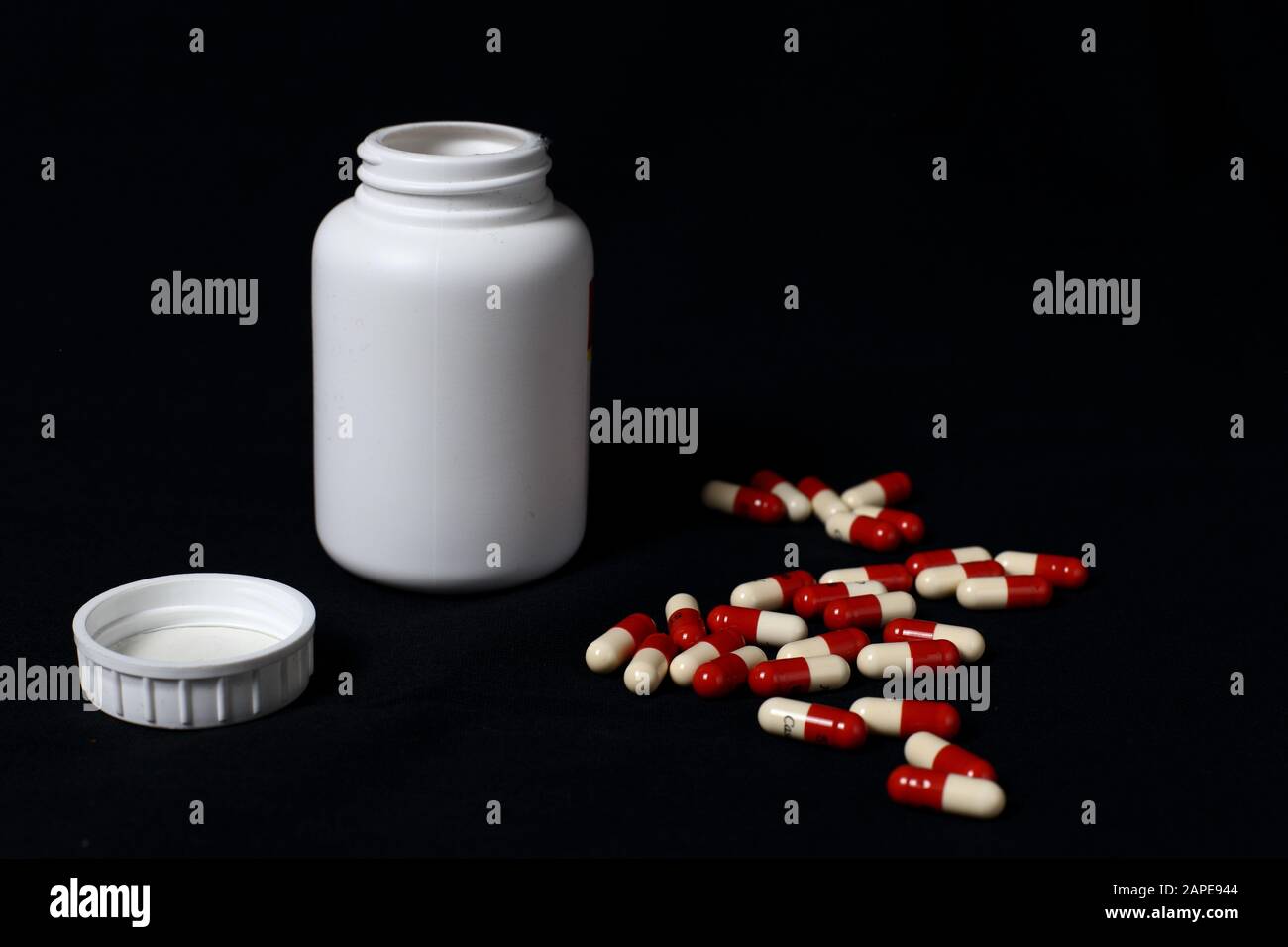 Stack of red and blue medicine capsules in front of a black background ...