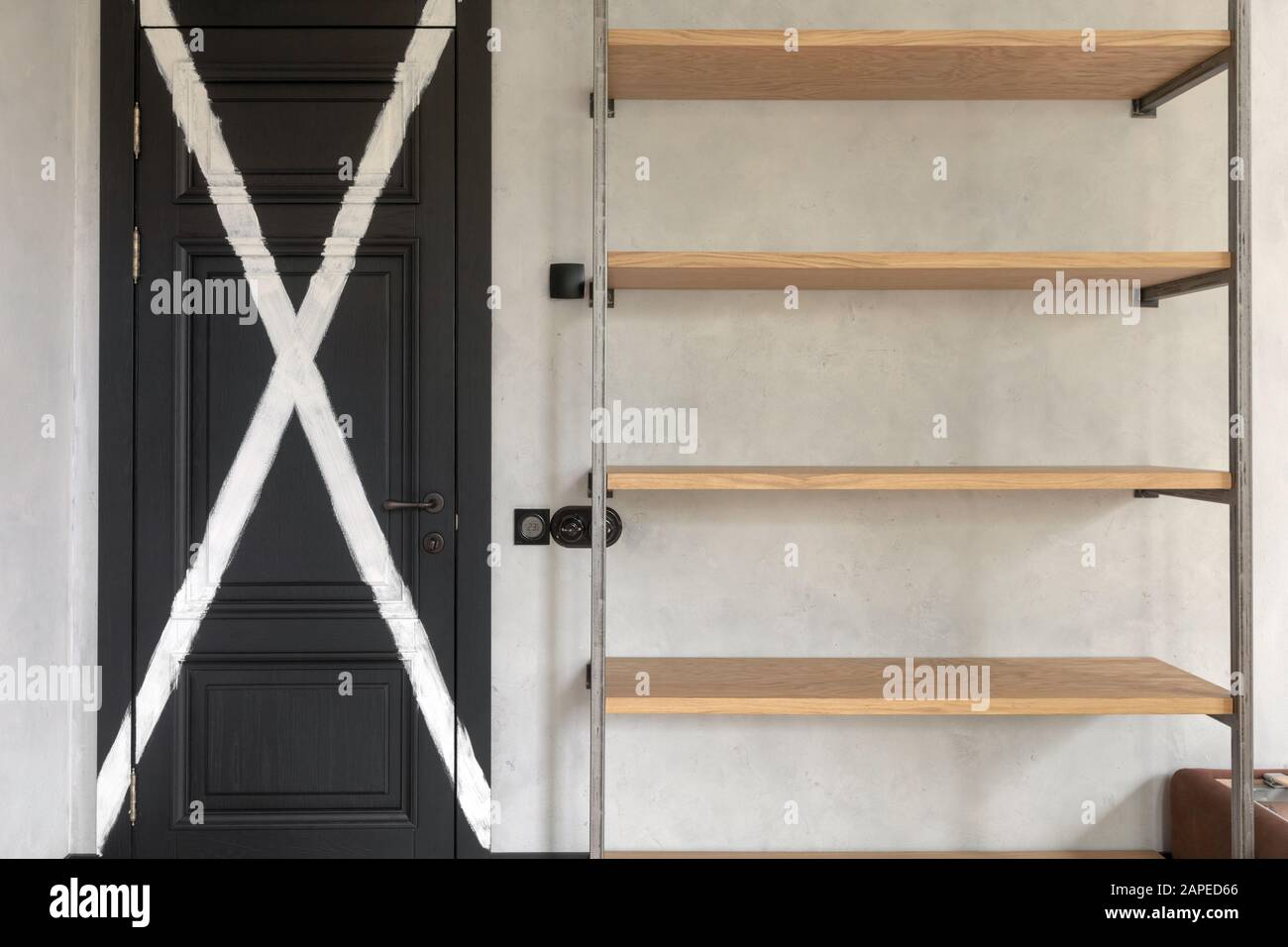 Black wooden door marked with white cross beside empty rack Stock Photo ...