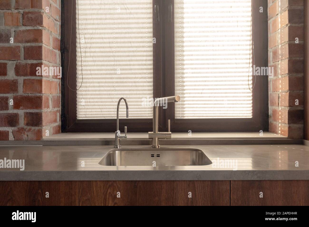 Kitchen sink with few faucets next to window and brick wall Stock Photo ...