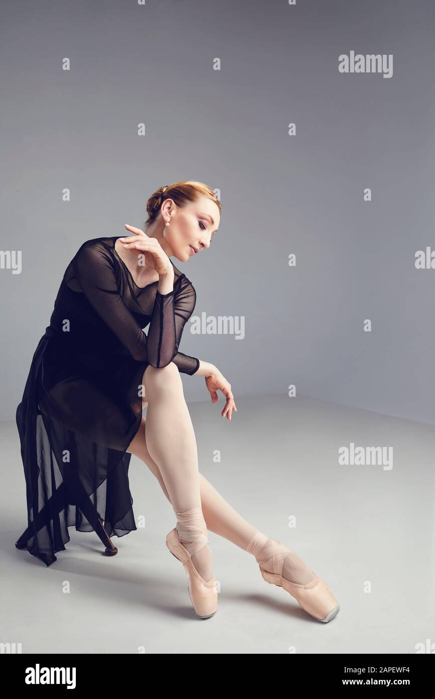 Dancer woman in black dress posing sitting on a chair Stock Photo - Alamy