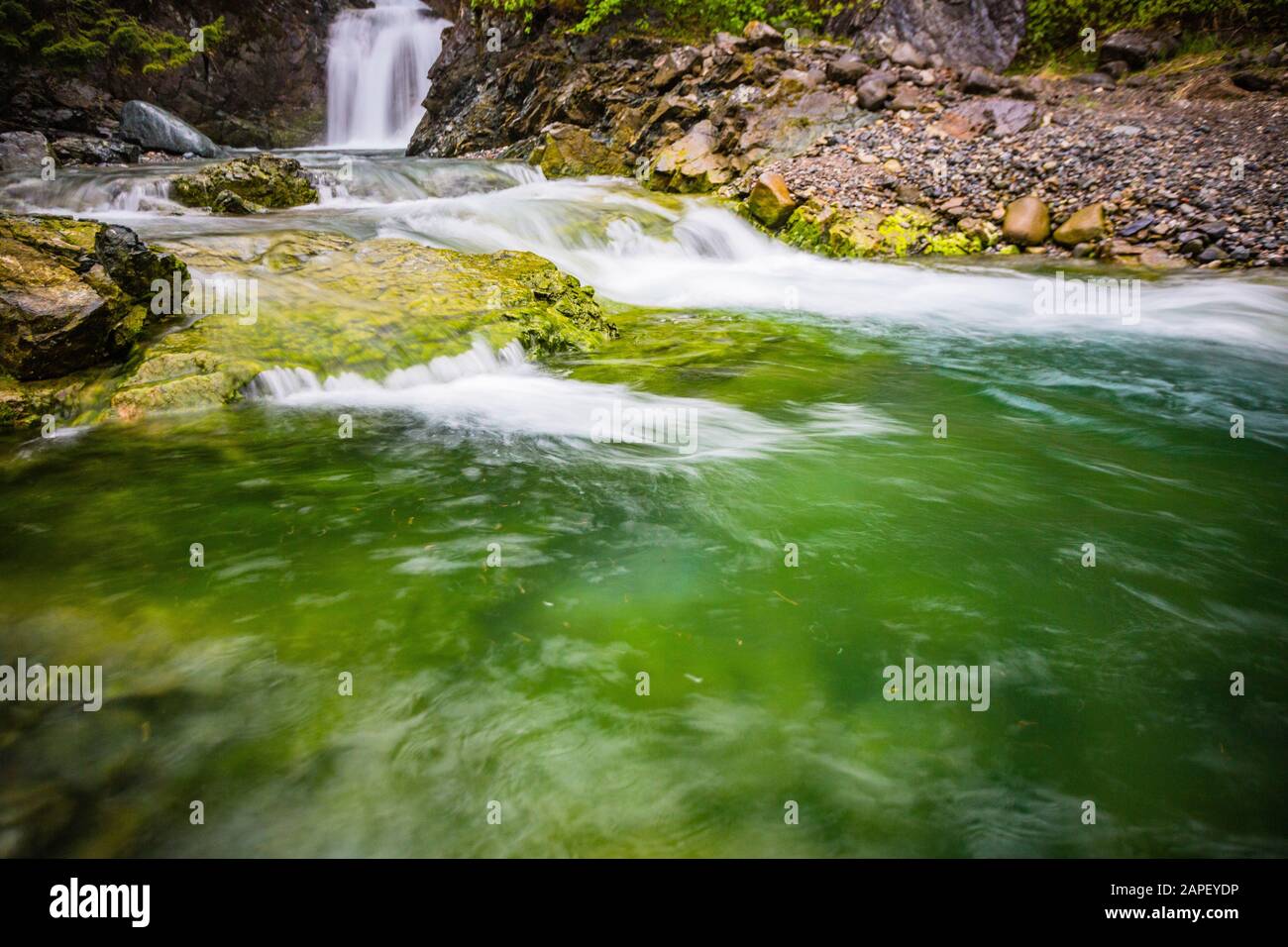 A waterfall flows into the frame from the forest Stock Photo - Alamy