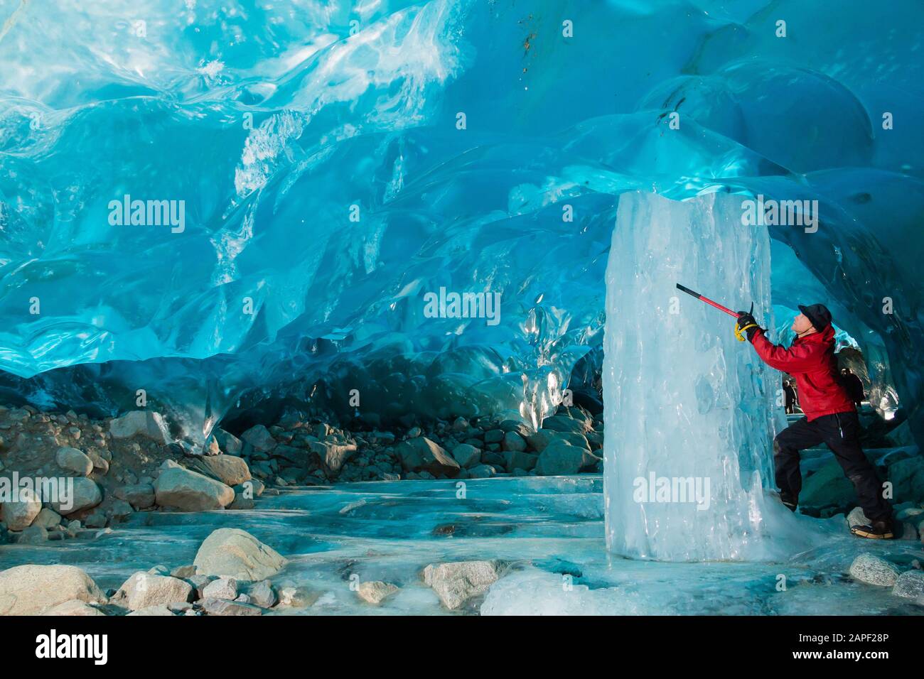 An explorer investigates an ice column within an ice cave of intense ...