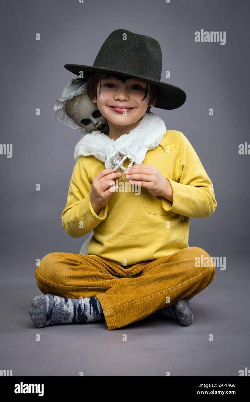 Cheerful little boy in a hat holds a spook, graybackground. Halloween ...