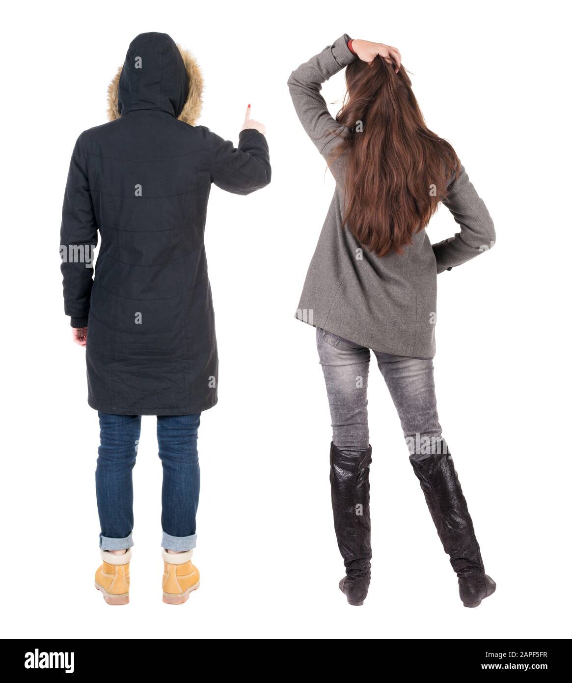 Back view of two pointing young girl in winter jacket. Rear view people ...