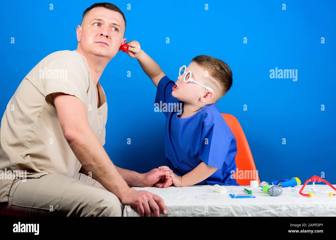 Kid little doctor sit table medical tools. Illness treatment. Dad and ...