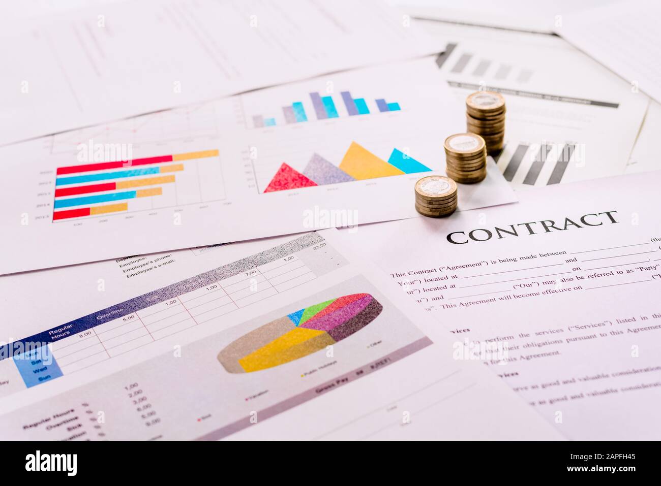 Coins stacked on documents of an economic contract Stock Photo - Alamy