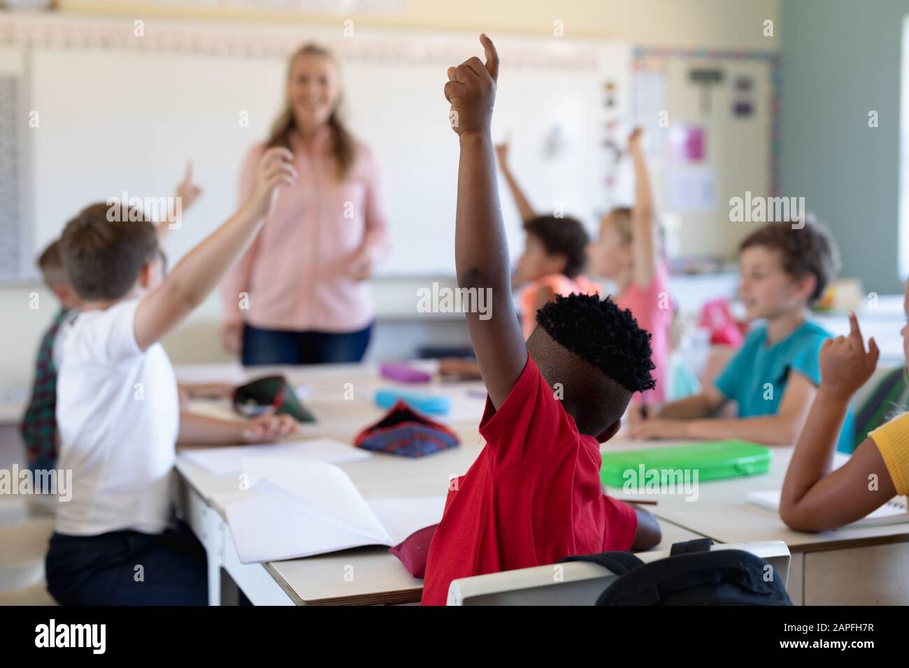 Group of schoolchildren raising their hands in an elementary school ...