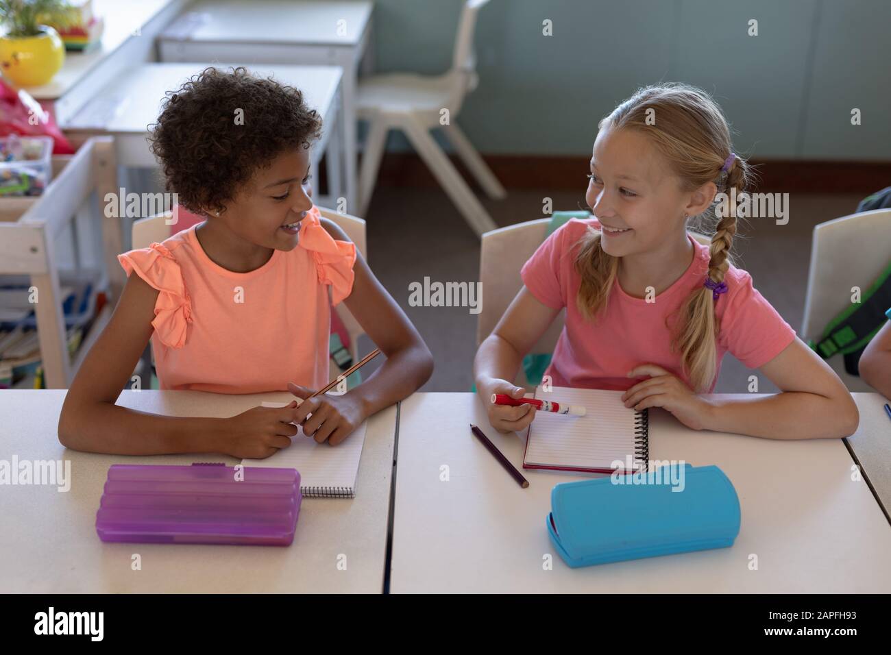 Schoolgirls talking during a lesson in an elementary school classroom ...