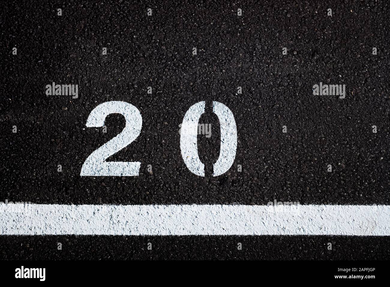 Number 20, painted on the paved ground of a parking lot with white ...