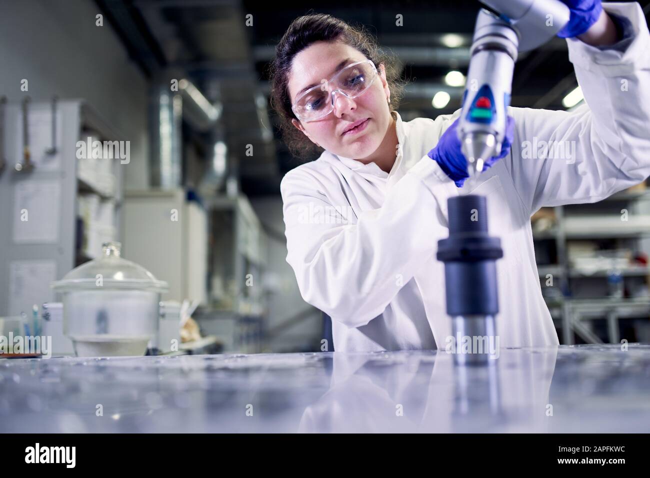 Woman lab technician in blue rubber gloves with 3D printer on defocused ...