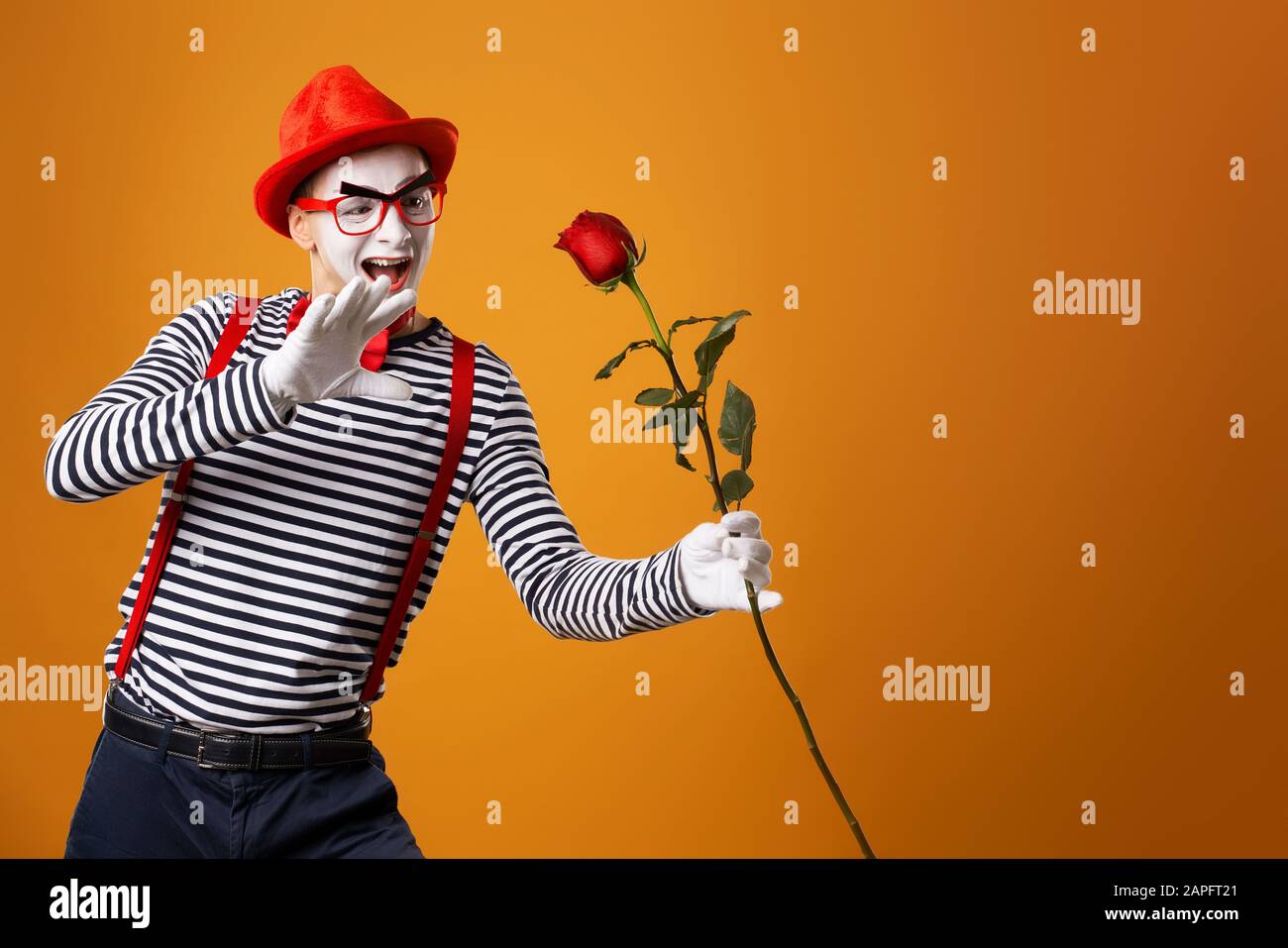 Funny mime man with white face in red hat and striped t-shirt holding ...