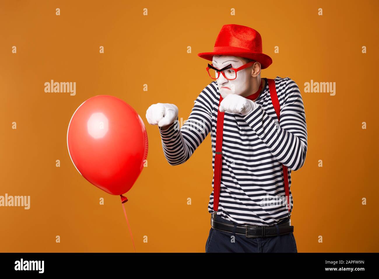 Angry mime with red ball on blank orange background Stock Photo - Alamy