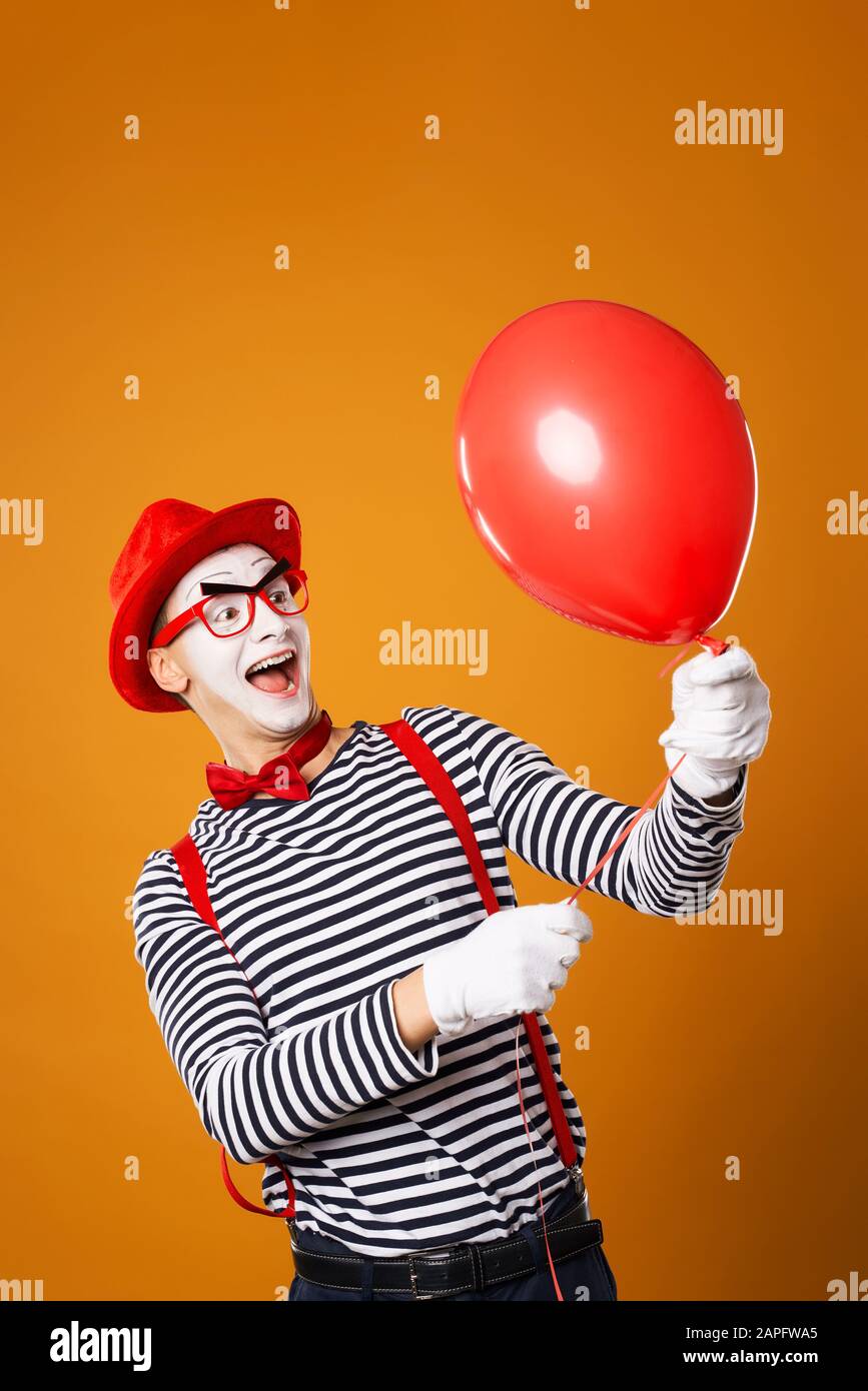 Cheerful clown mime with red ball on blank orange background Stock ...