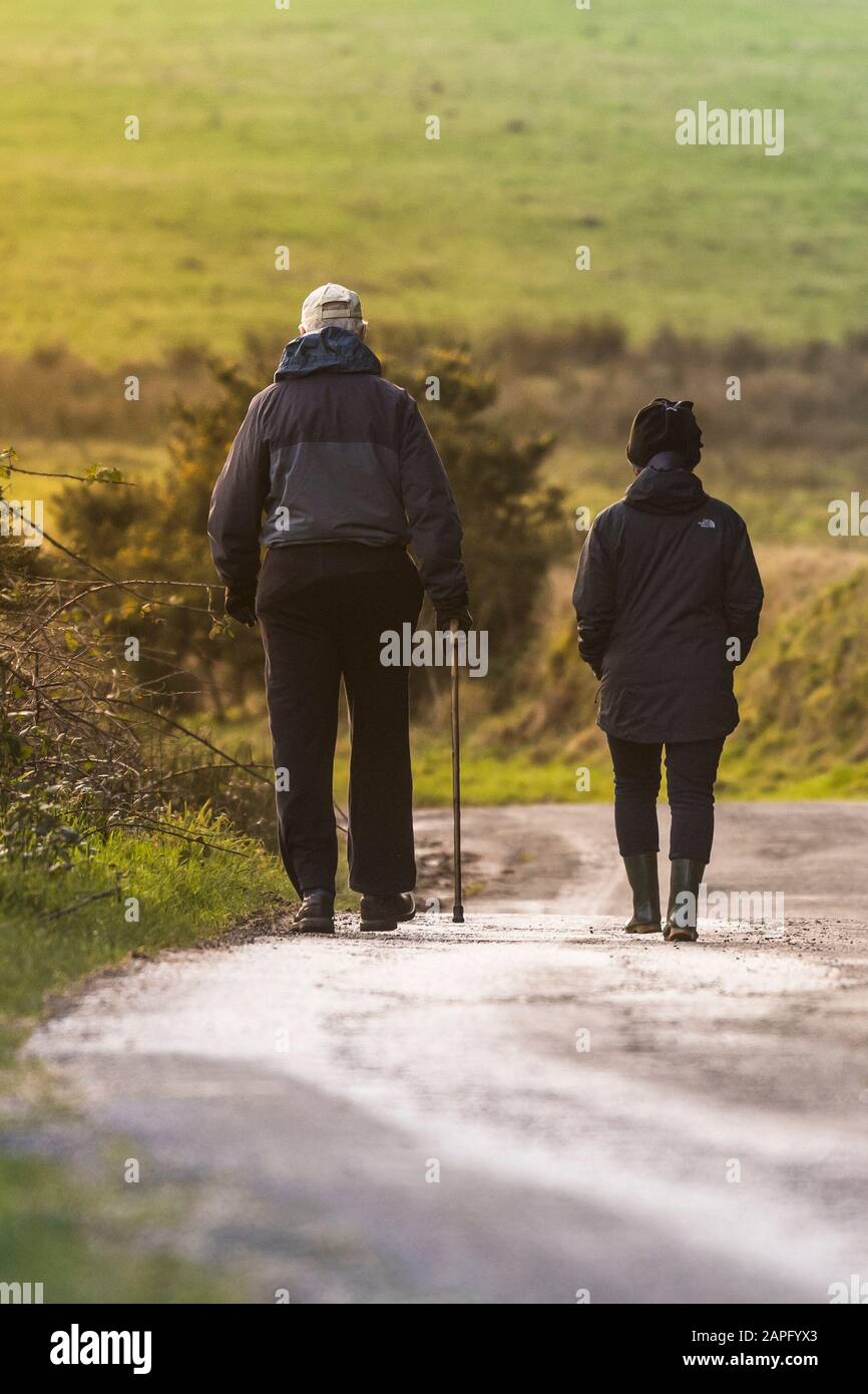 A mature couple strolling along a country road in evening light in ...