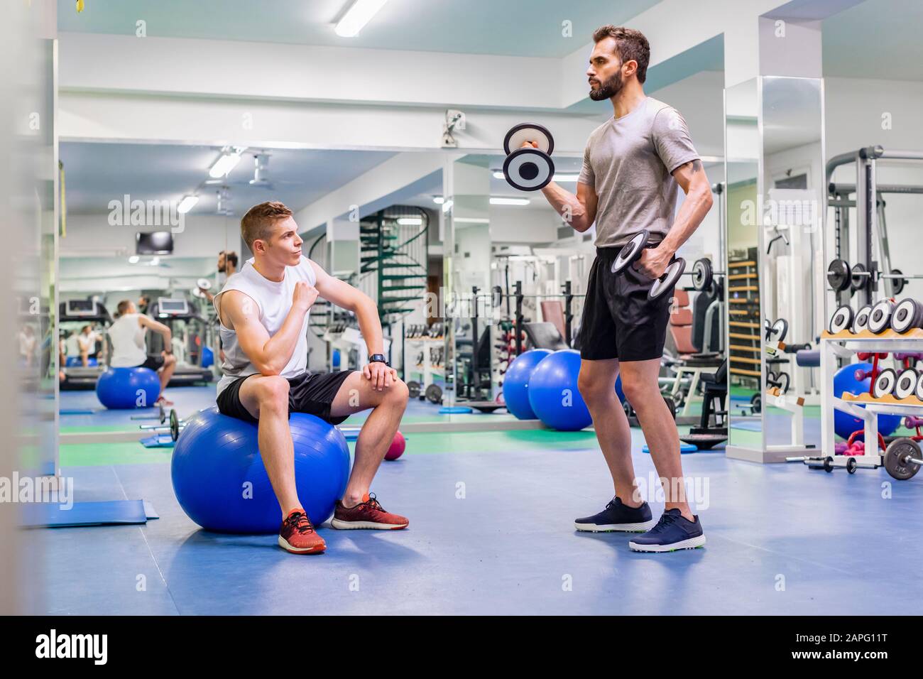 Man coaching friend in gym Stock Photo - Alamy